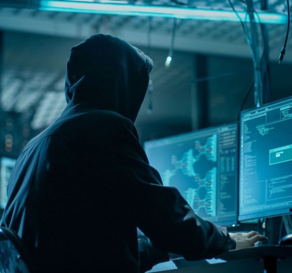 Abbildung einer Person mit Kapuze vor einem Computermonitor